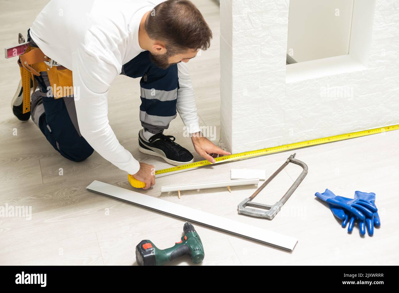 A man installs a floor skirting board. Fixing the plastic skirting ...