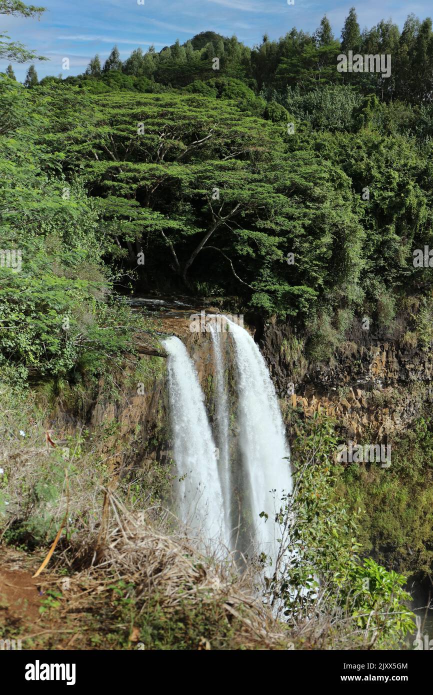 Three waterfalls cascading over a volcanic cliffside surrounded by rain ...