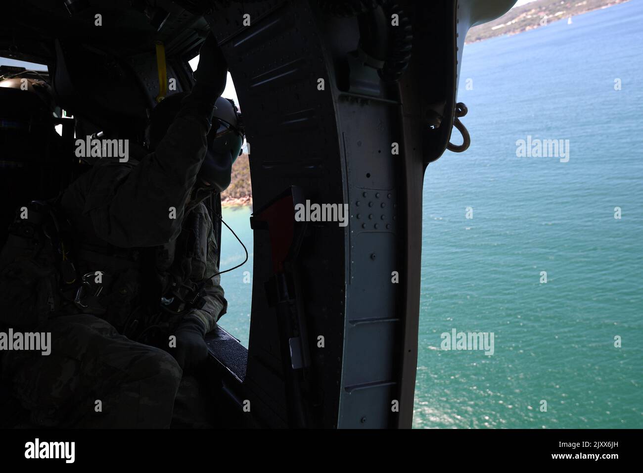 An Australian Army loadmaster looks out from a Black Hawk helicopter ...