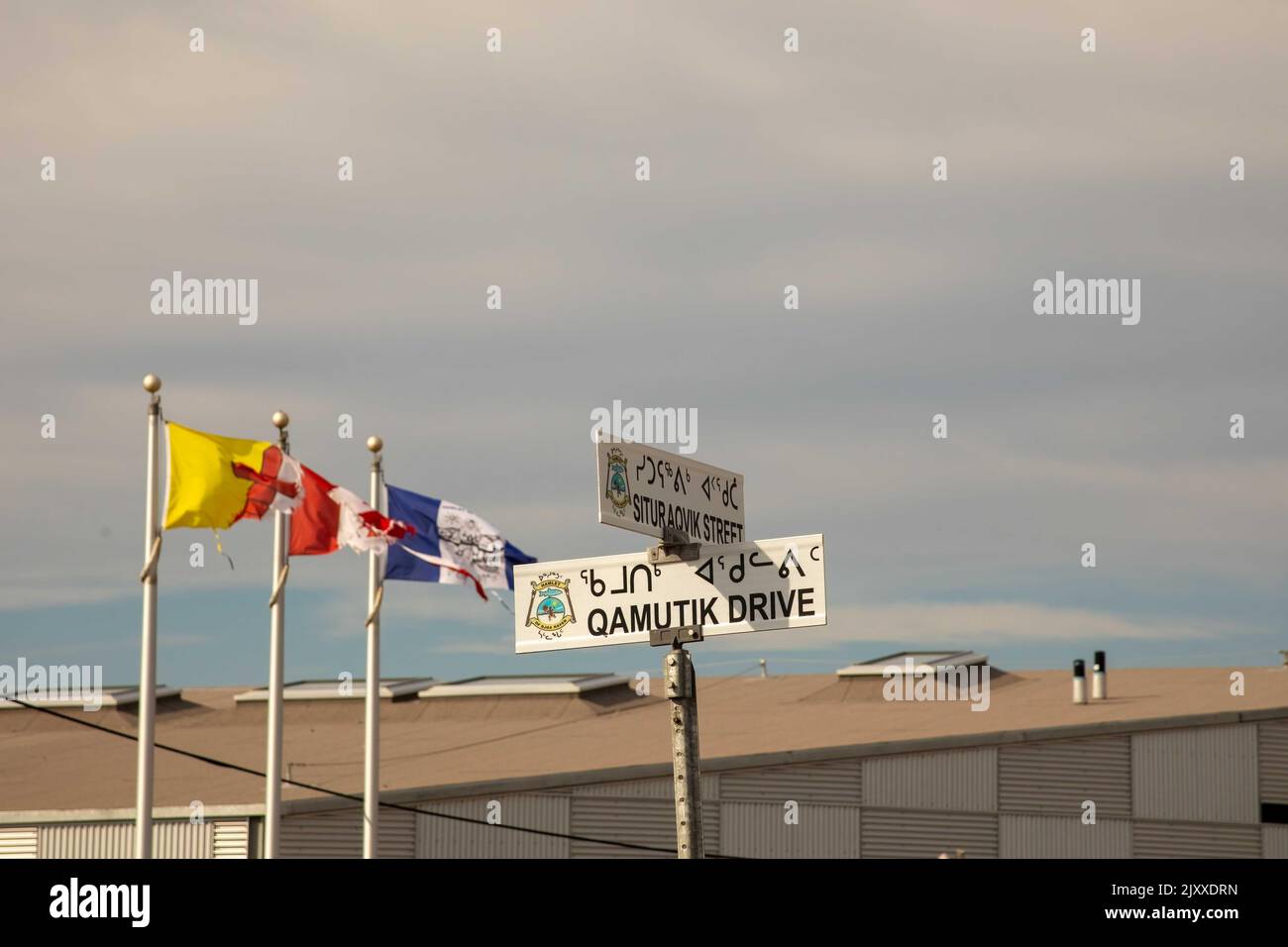 Street signs in indigenous language with flags of Nunavut, Canada and ...