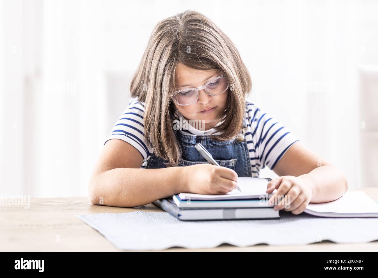Bored girl writes homework into an exercise book Stock Photo - Alamy