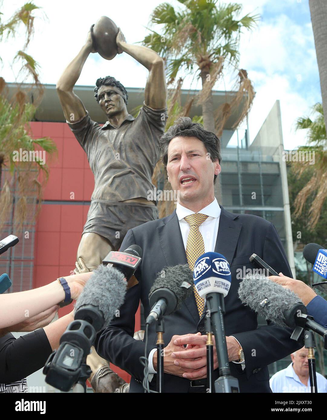 Rugby great John Eales speaks to the media in front of a bronze statue ...