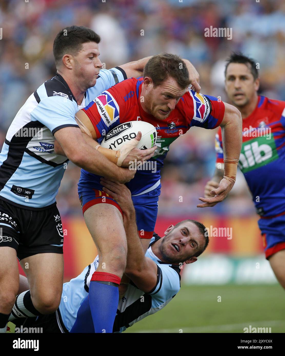 Tim Glasby of the Knights is tackled during the Round 1 NRL match ...