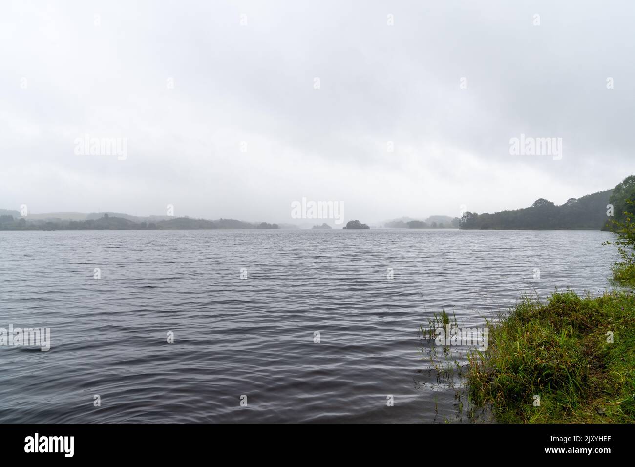 Landscape view of misty and foggy atmosphere over a calm lake ...