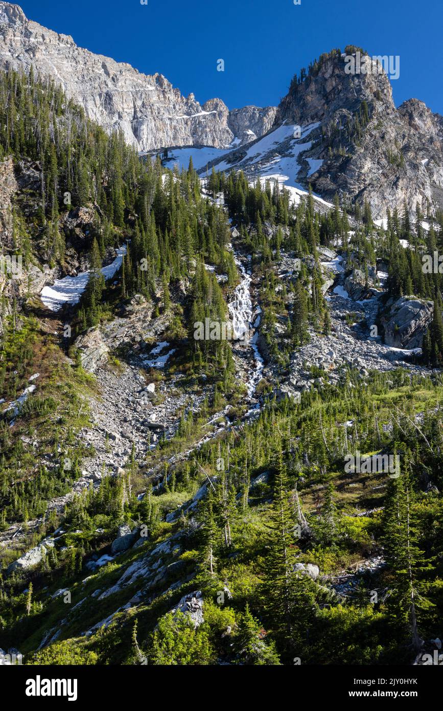 A large waterfall pouring from the high cliffs and peaks of Paintbrush Canyon in the Teton ...