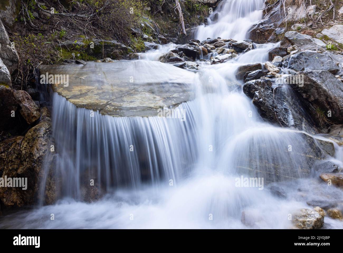 A small creek pouring over rocky waterfalls in Paintbrush Canyon. Grand Teton National Park ...