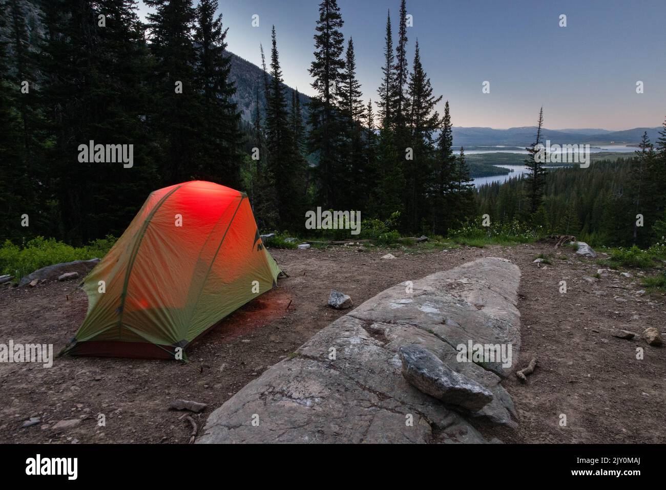 A backpacking tent glowing red from a headlamp above Leigh and Jackson ...