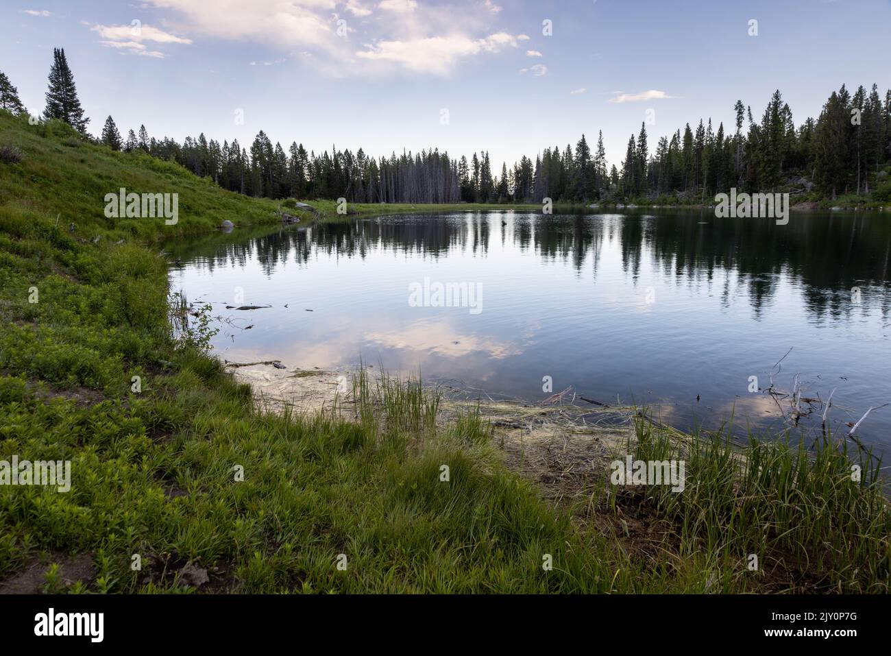 The calm waters of Trapper Lake reflecting whispy clouds passing ...