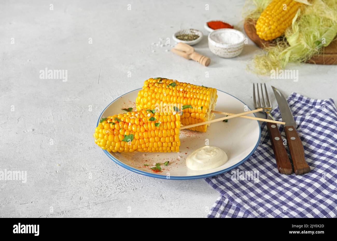 Plate with tasty Corn on white background, spices at the bakground ...