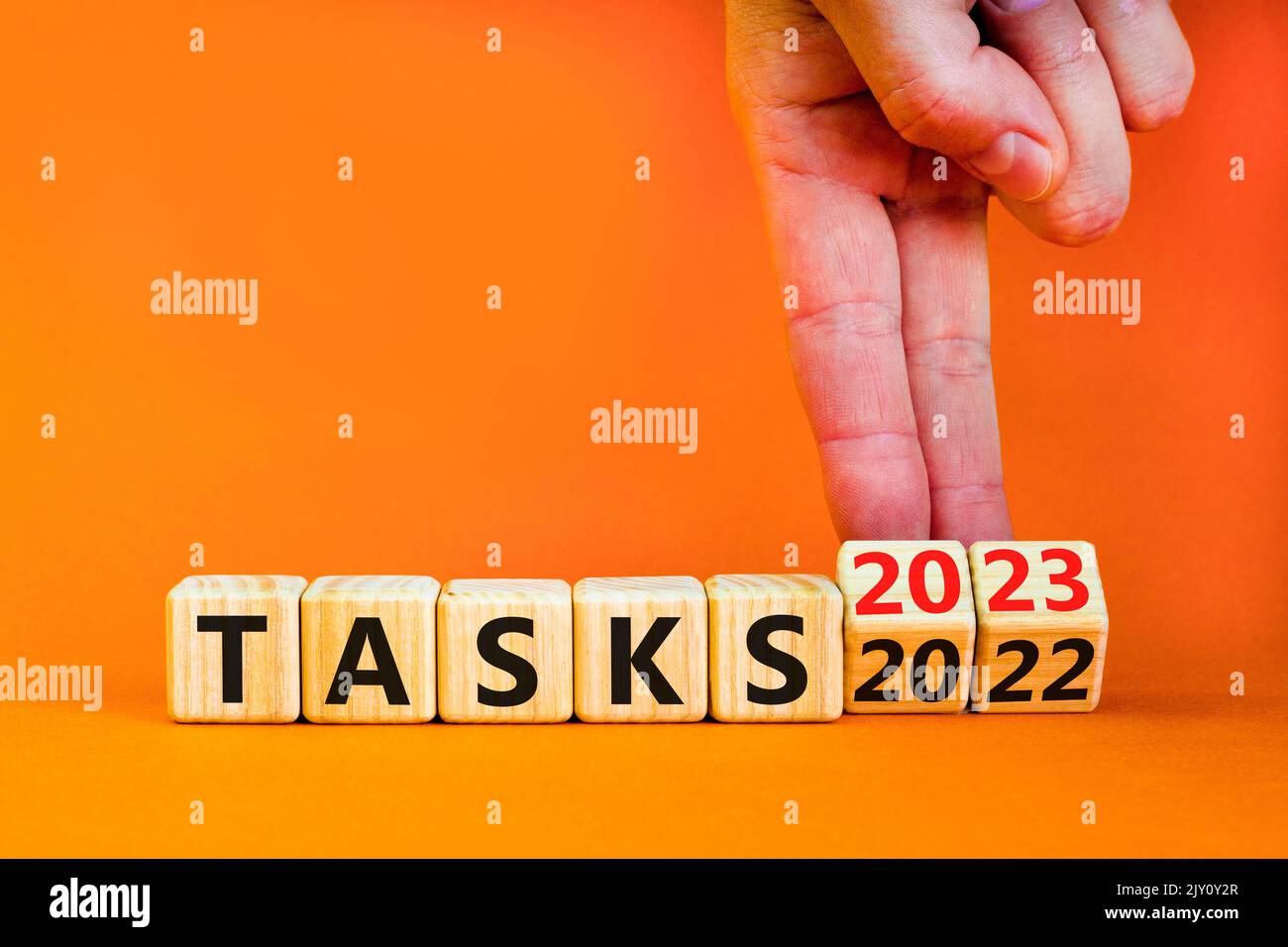 2023 tasks new year symbol. Businessman turns a wooden cube and changes words Tasks 2022 to ...