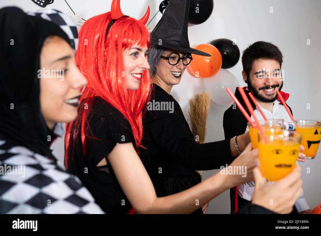 Halloween party at home. Devil, witch, dracula and harlequin smiling ...