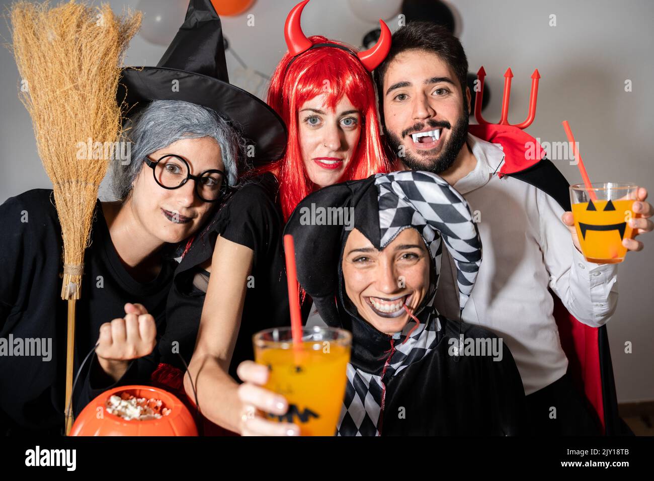 Halloween party at home. Devil, witch, dracula and harlequin posing and ...