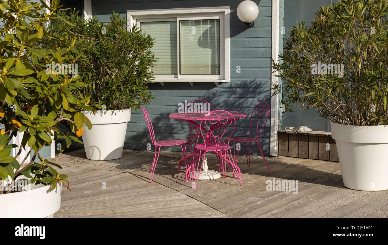 Bright pink outdoor patio set and large white plant pots next to a ...