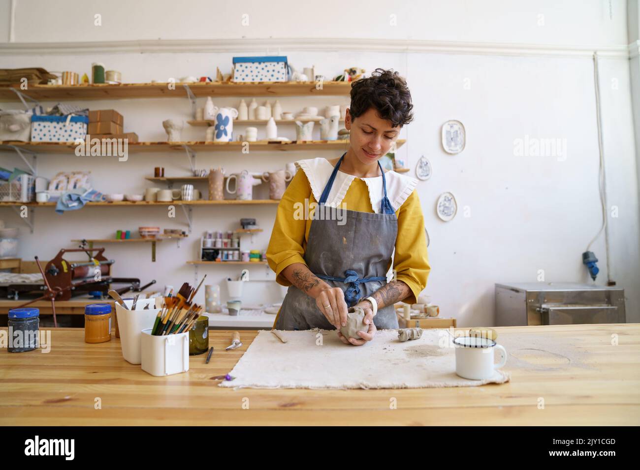 Happy ceramist girl in workshop studio prepare raw clay for shaping at ...