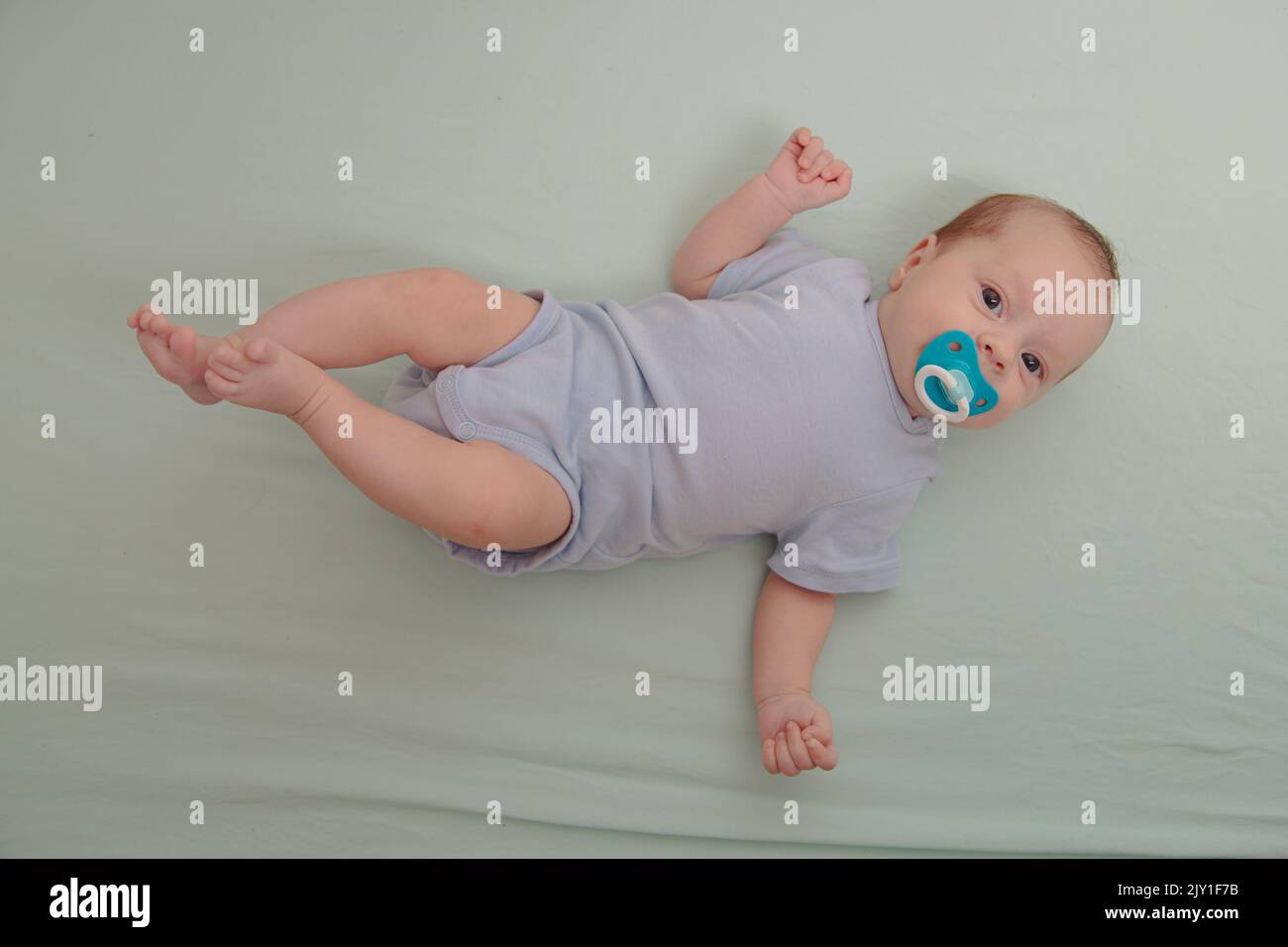 The baby is lying in his crib and looking at the camera . Happy baby ...