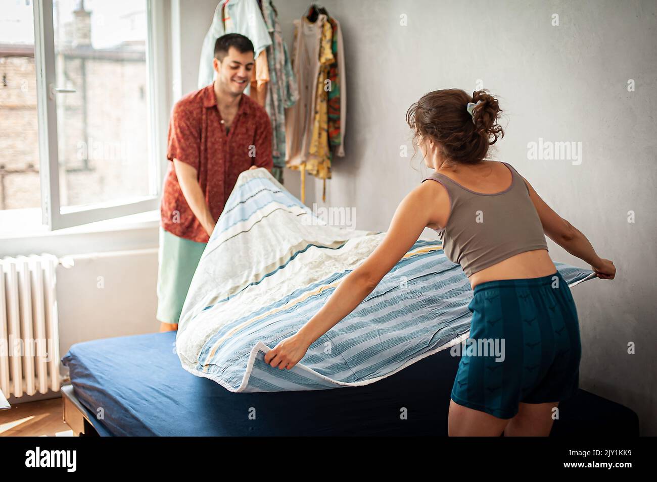 Cheerful Young Couple Making Bed Having Fun At Home Doing House