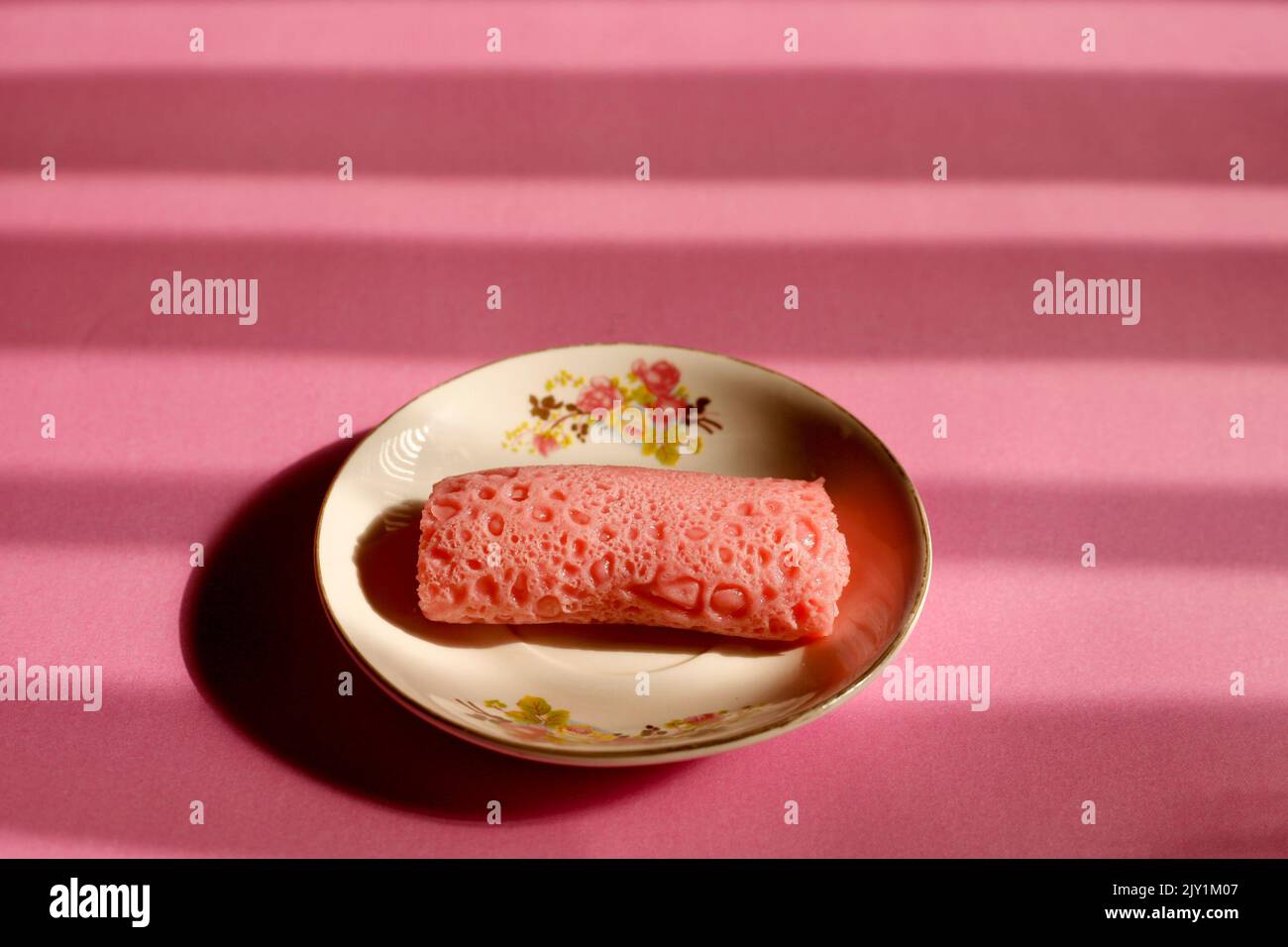 Pink pancake rolls on plate. Traditional Indonesian or Malayasian food ...