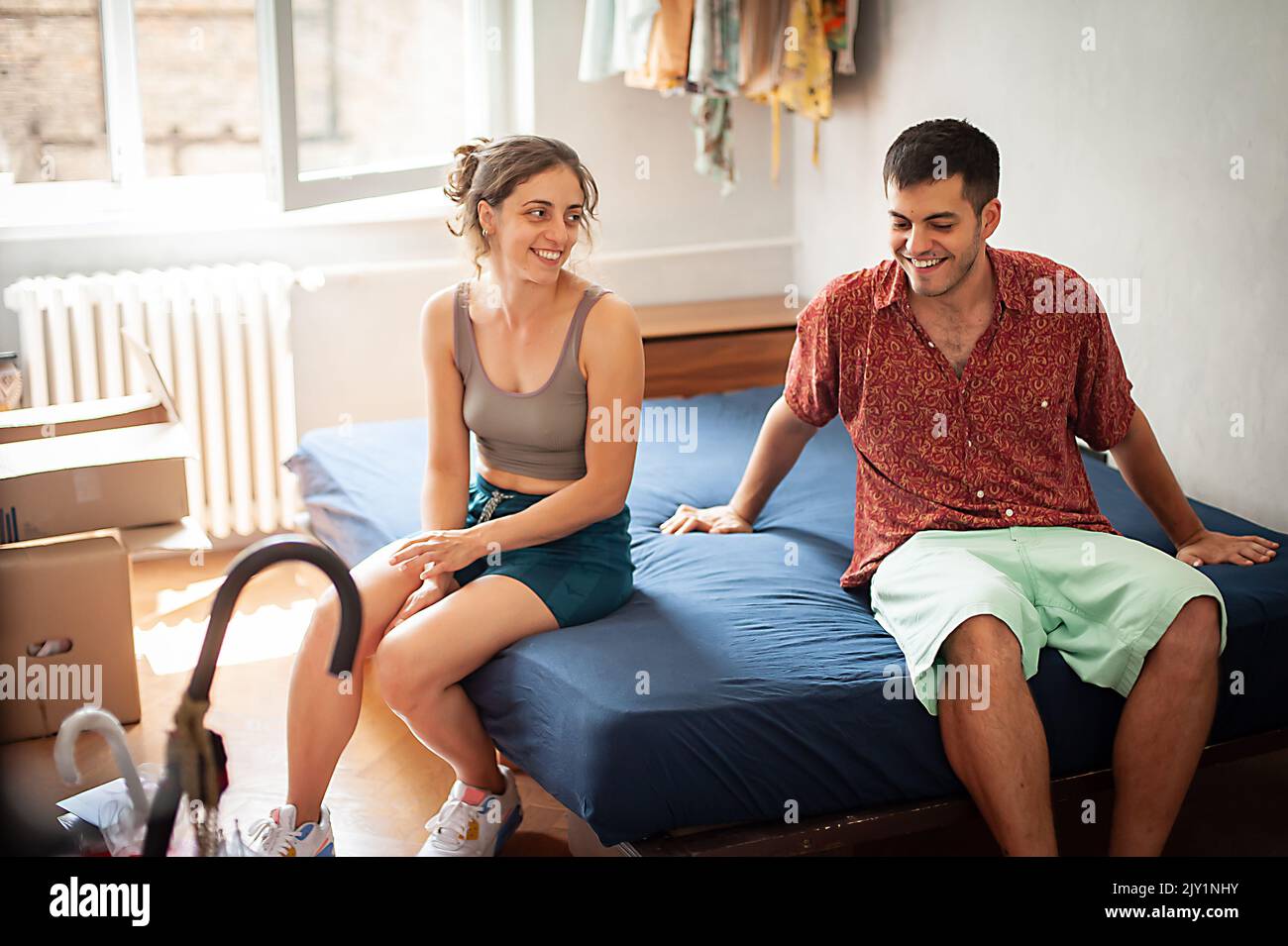 Cheerful young couple making bed, having fun at home. Doing house ...