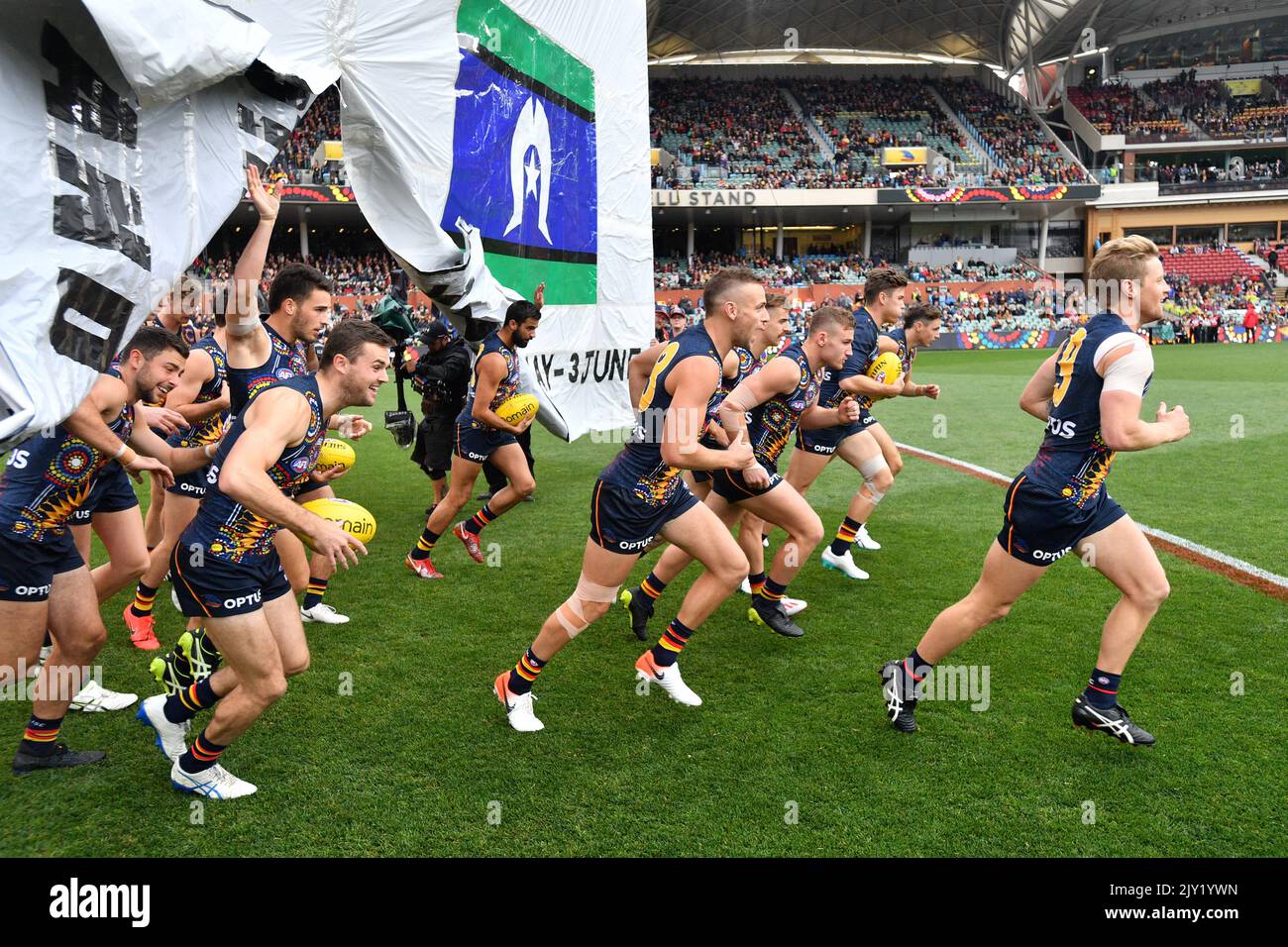 Crows players run through the banner during the Round 10 AFL match ...