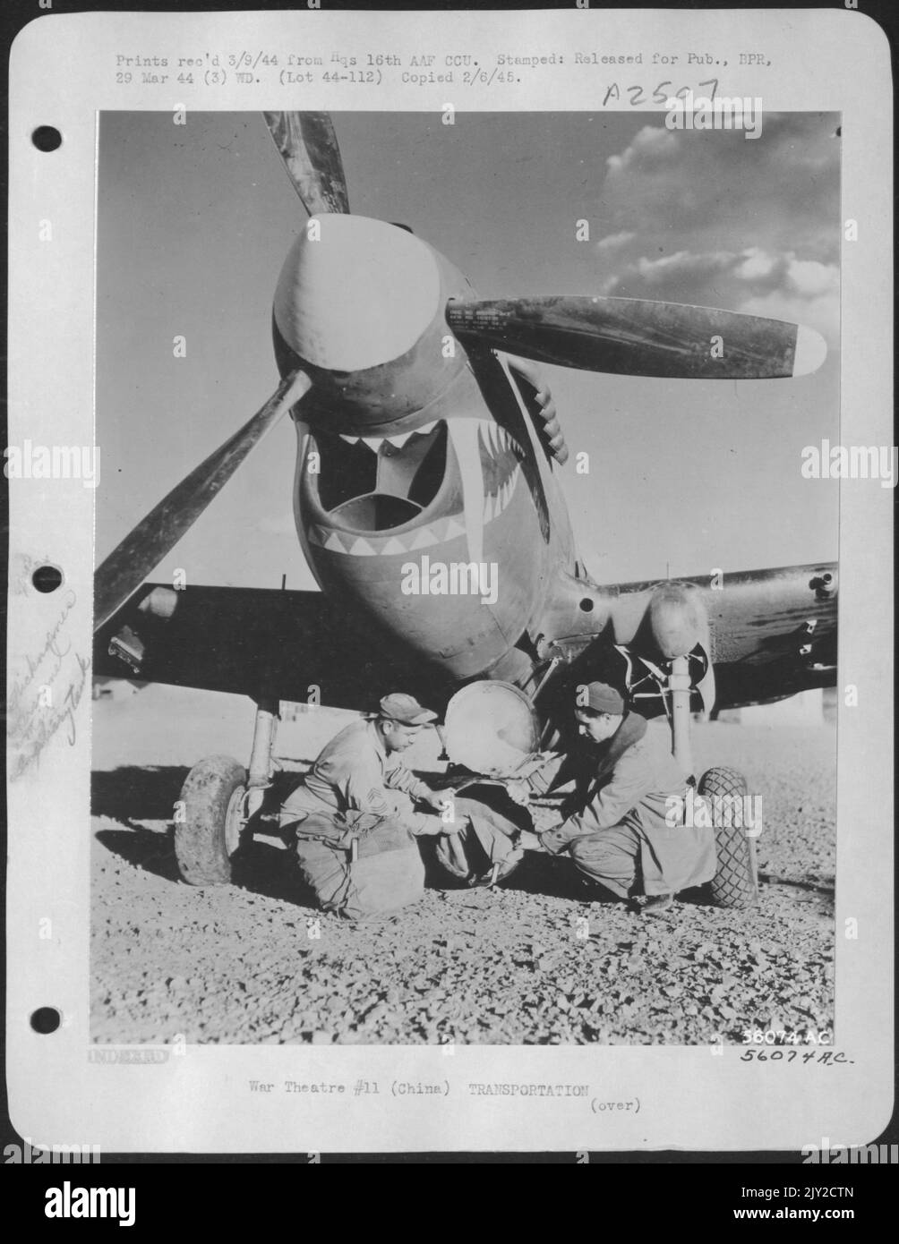 Installing a belly tank on a Curtis P-40 for carrying mail. Left to ...