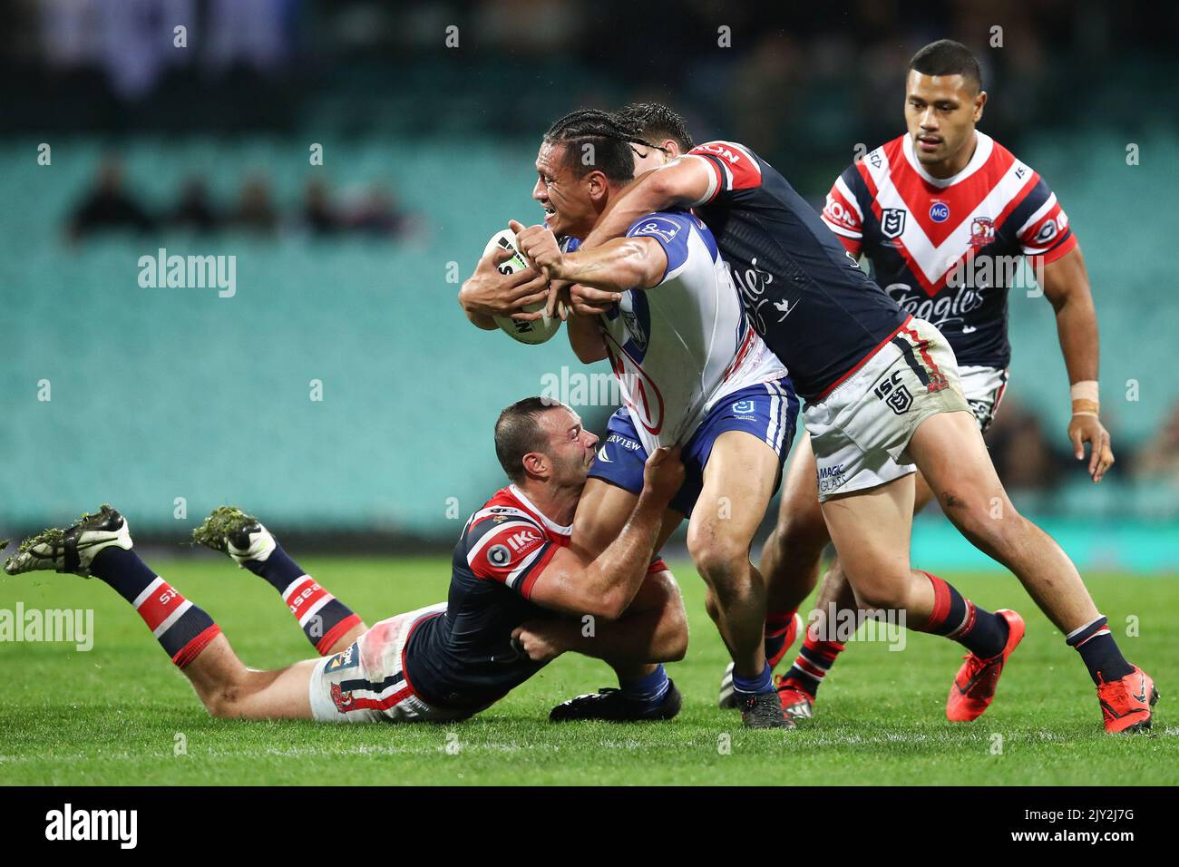 Sauaso Sue of the Bulldogs is tackled by the Roosters defence during ...