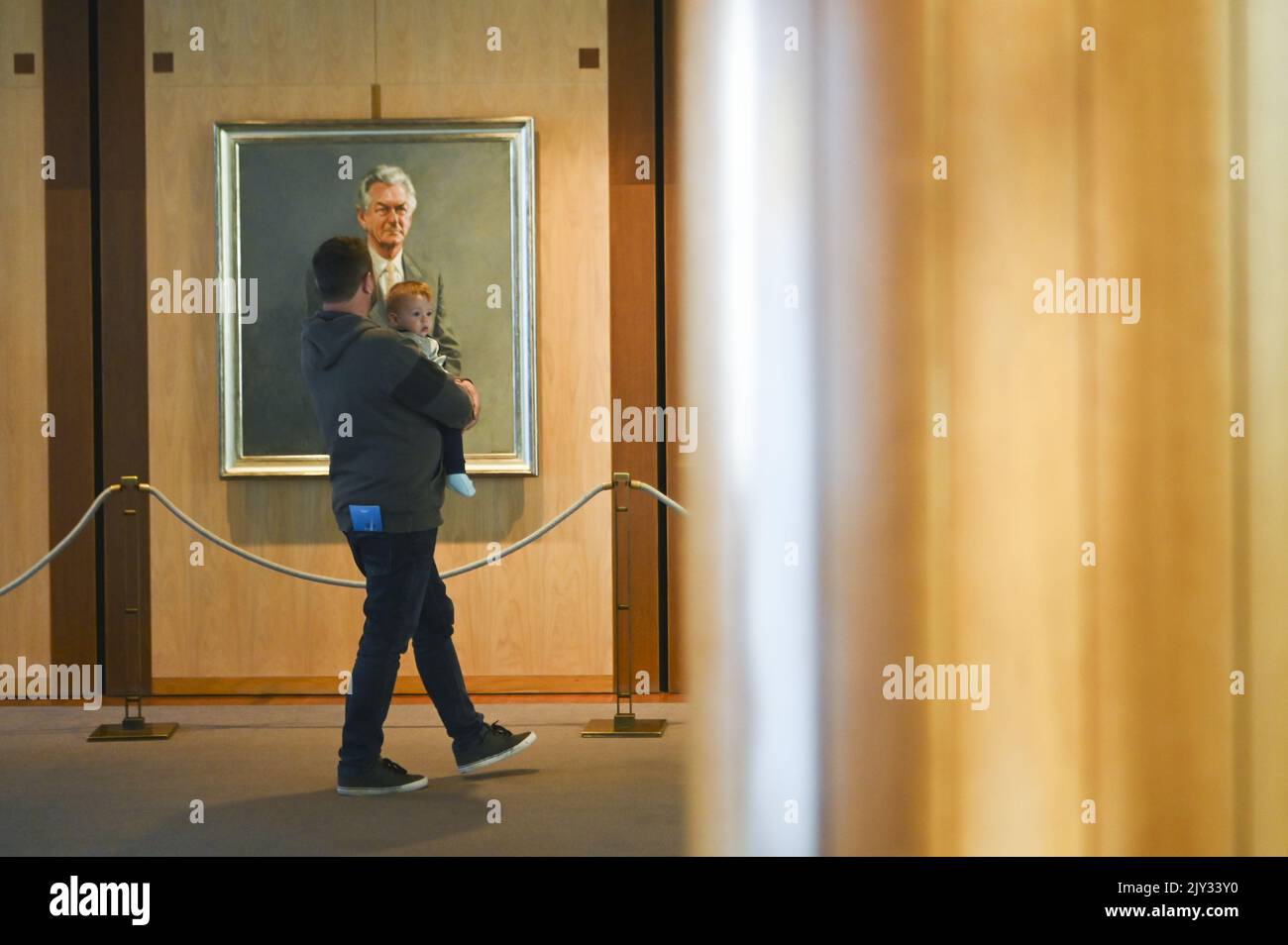 A visitor takes a look at the official portrait of the late former ...