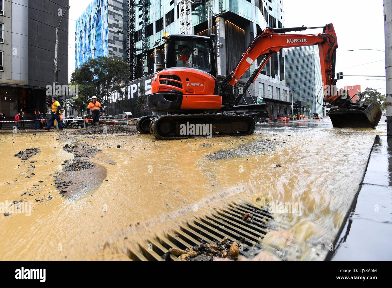 An excavator clears mud after a burst water pipe flooded Victoria ...