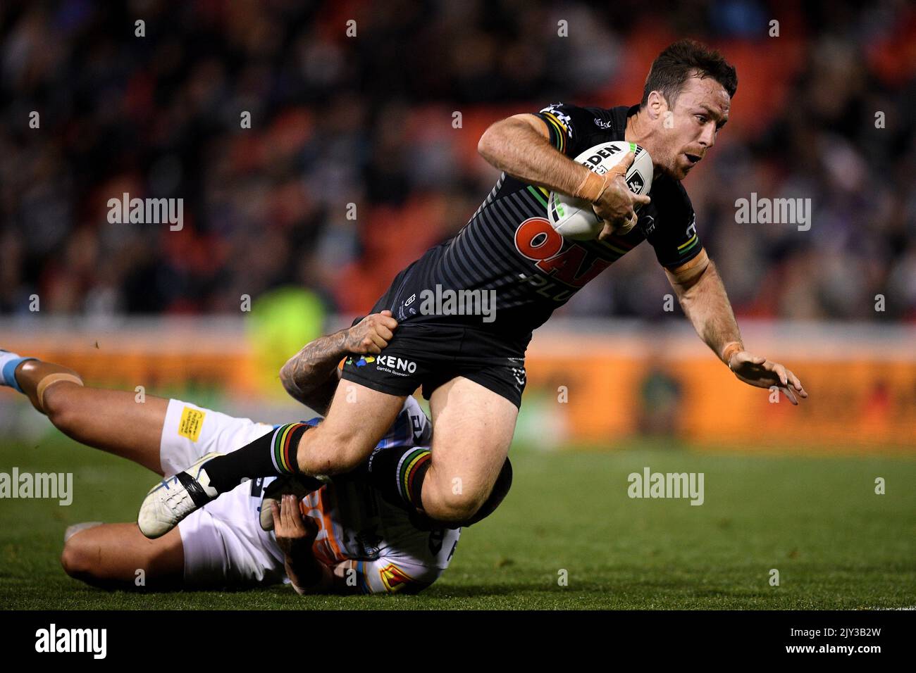 James Maloney of the Panthers is tackled by Nathan Peats of the Titans ...