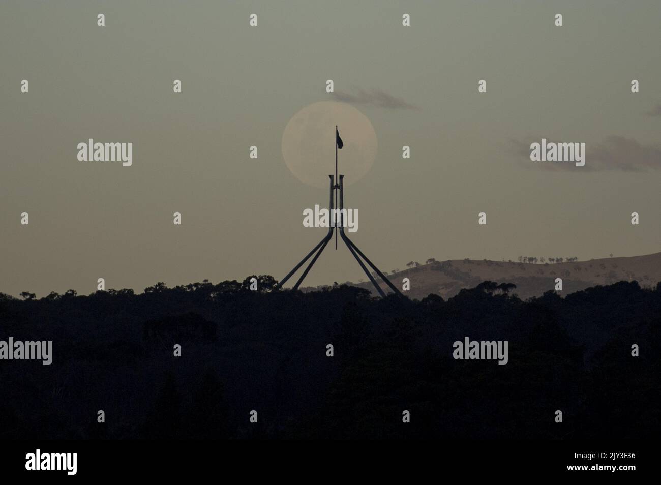A full moon rises behind Parliament House in Canberra, Tuesday, 16 July ...