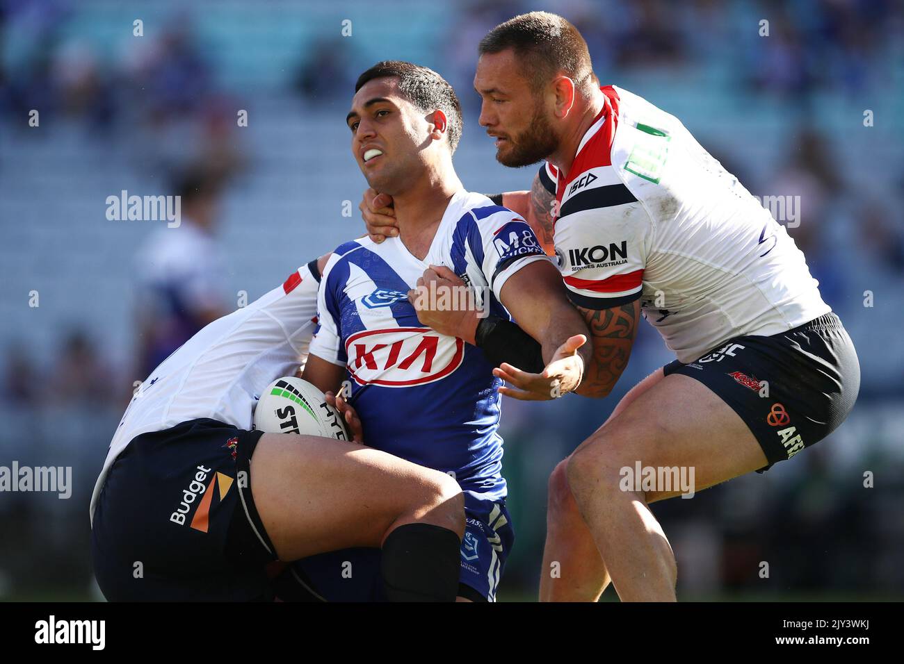 Reimis Smith of the Bulldogs is tackled by the Roosters defence during ...