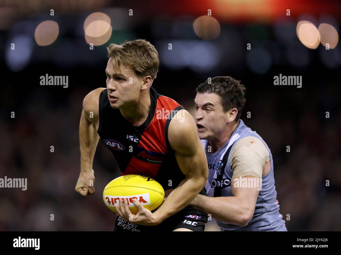 Dylan Clarke of the Bombers handballs under pressure from Tom Rockliffe ...