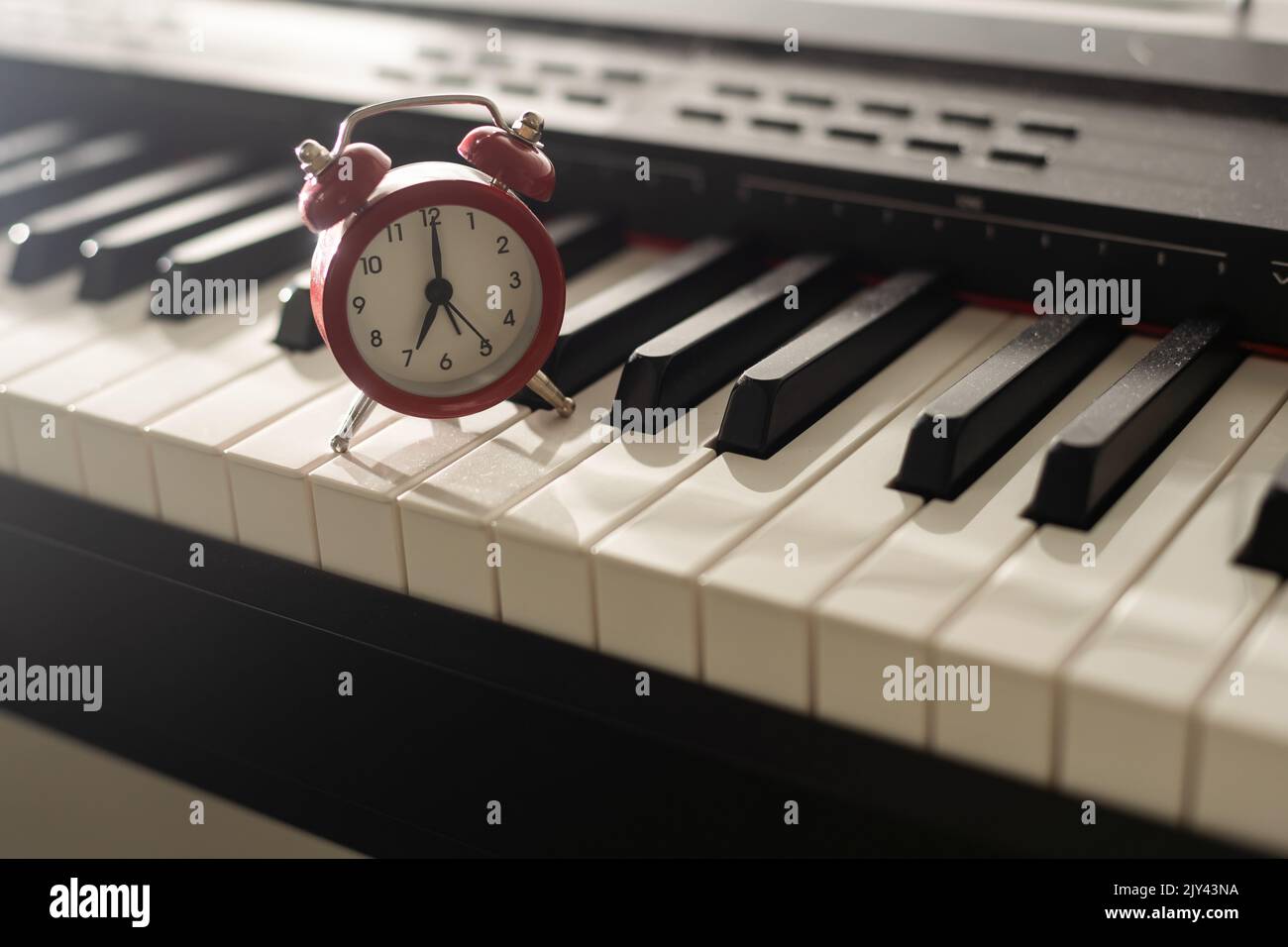 Piano and alarm clock, the time to practice the piano Stock Photo - Alamy