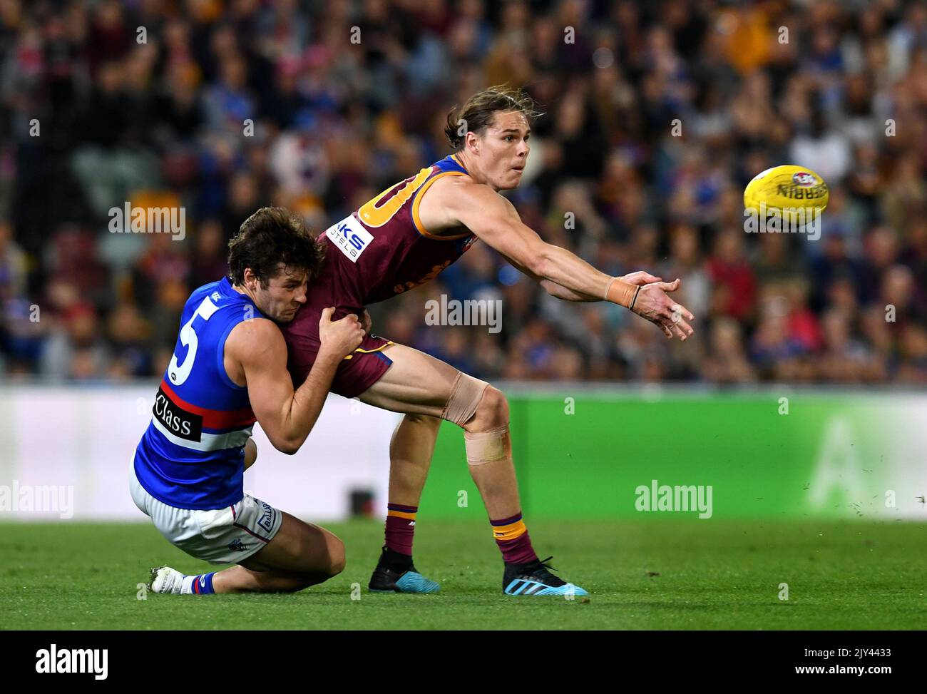 Eric Hipwood of the Lions (right) is tackled by Josh Dunkley of the ...