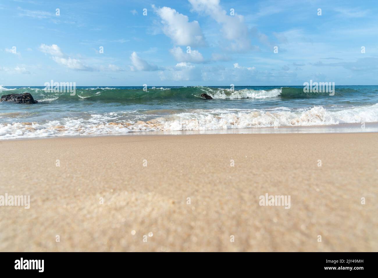 Low view of a beach against blue sky with clouds in the background ...