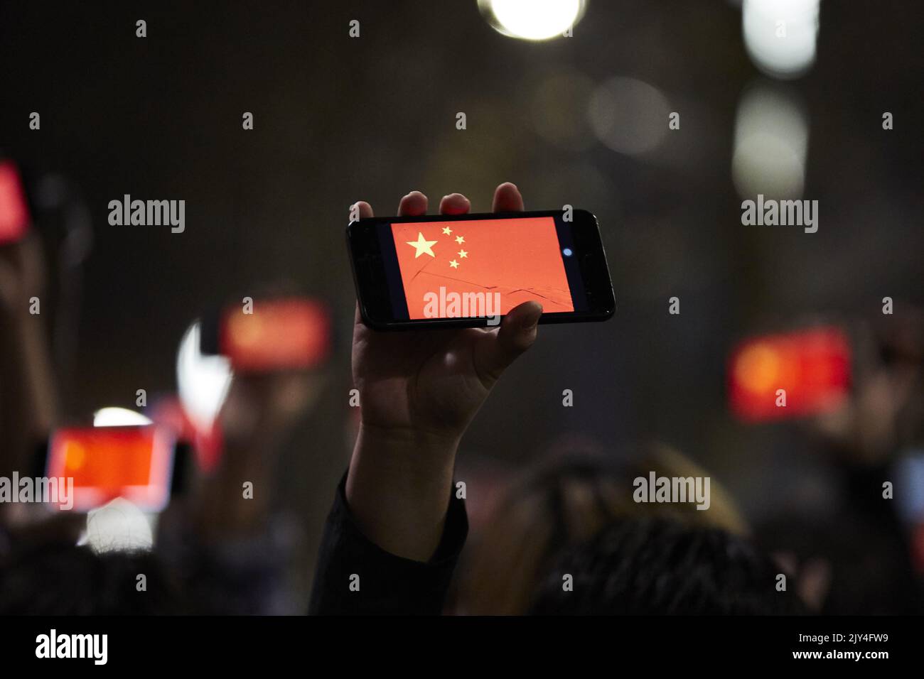 Pro-China counter protesters hold up phones showing the Chinese ...