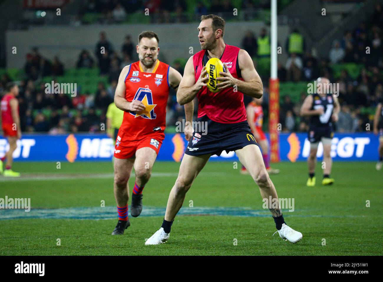 Travis Cloke of the Vics looks to kick while being chased by Anthony ...