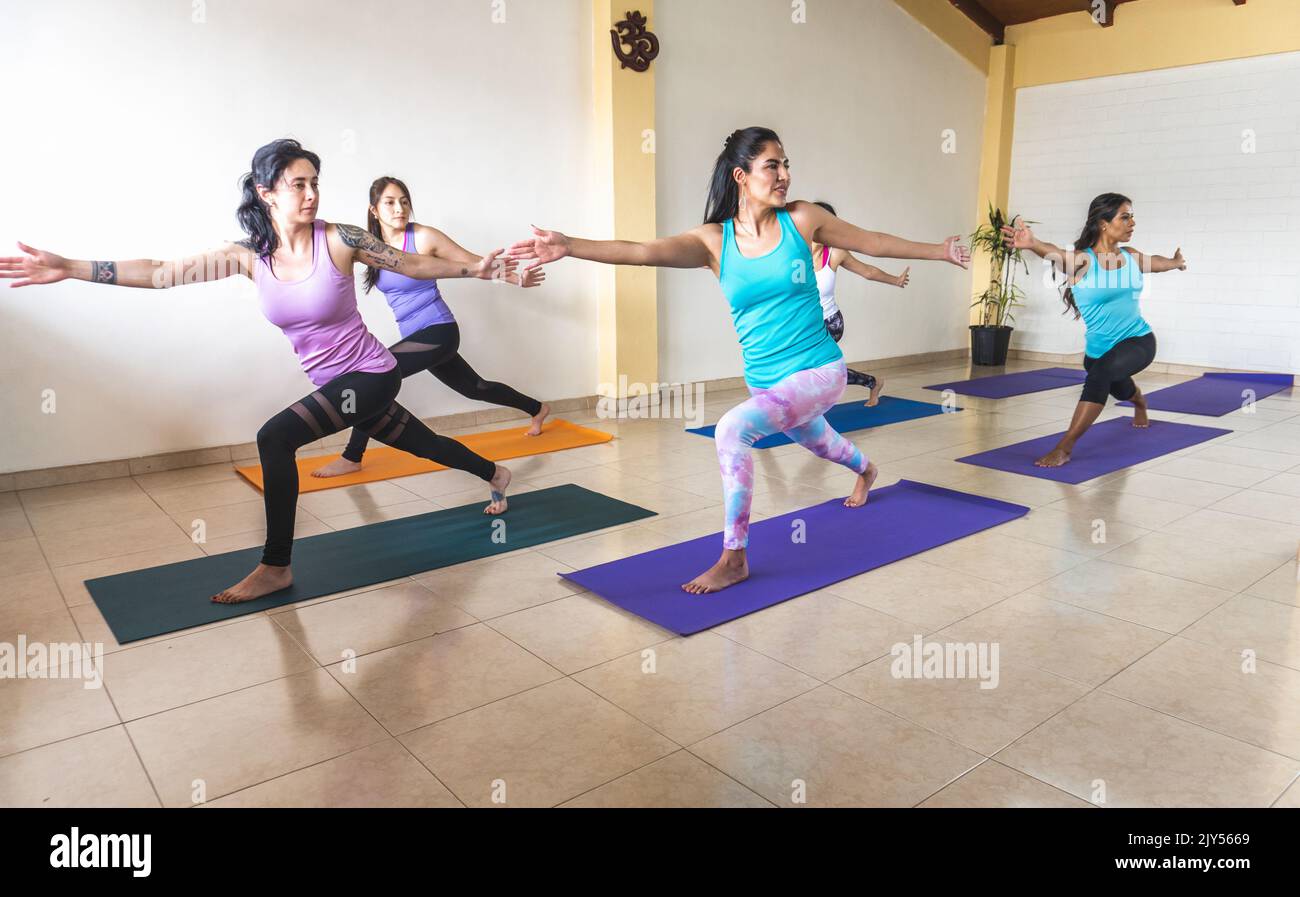 Women in yoga warrior pose standing sideways with arms open one leg ...