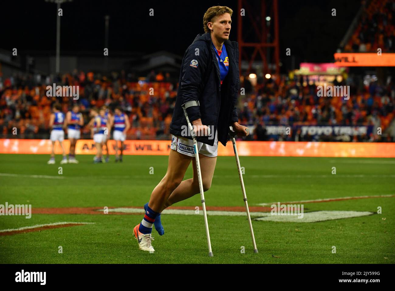 Aaron Naughton of the Bulldogs walks from the field on crutches during ...
