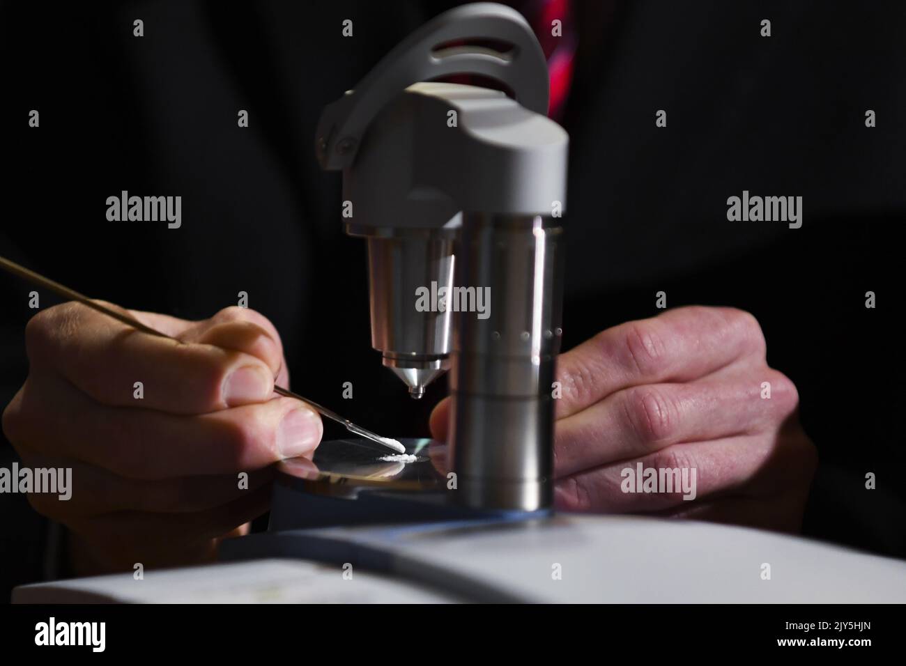 A man uses the Compact FTIR Spectrometer pill testing machine during a ...