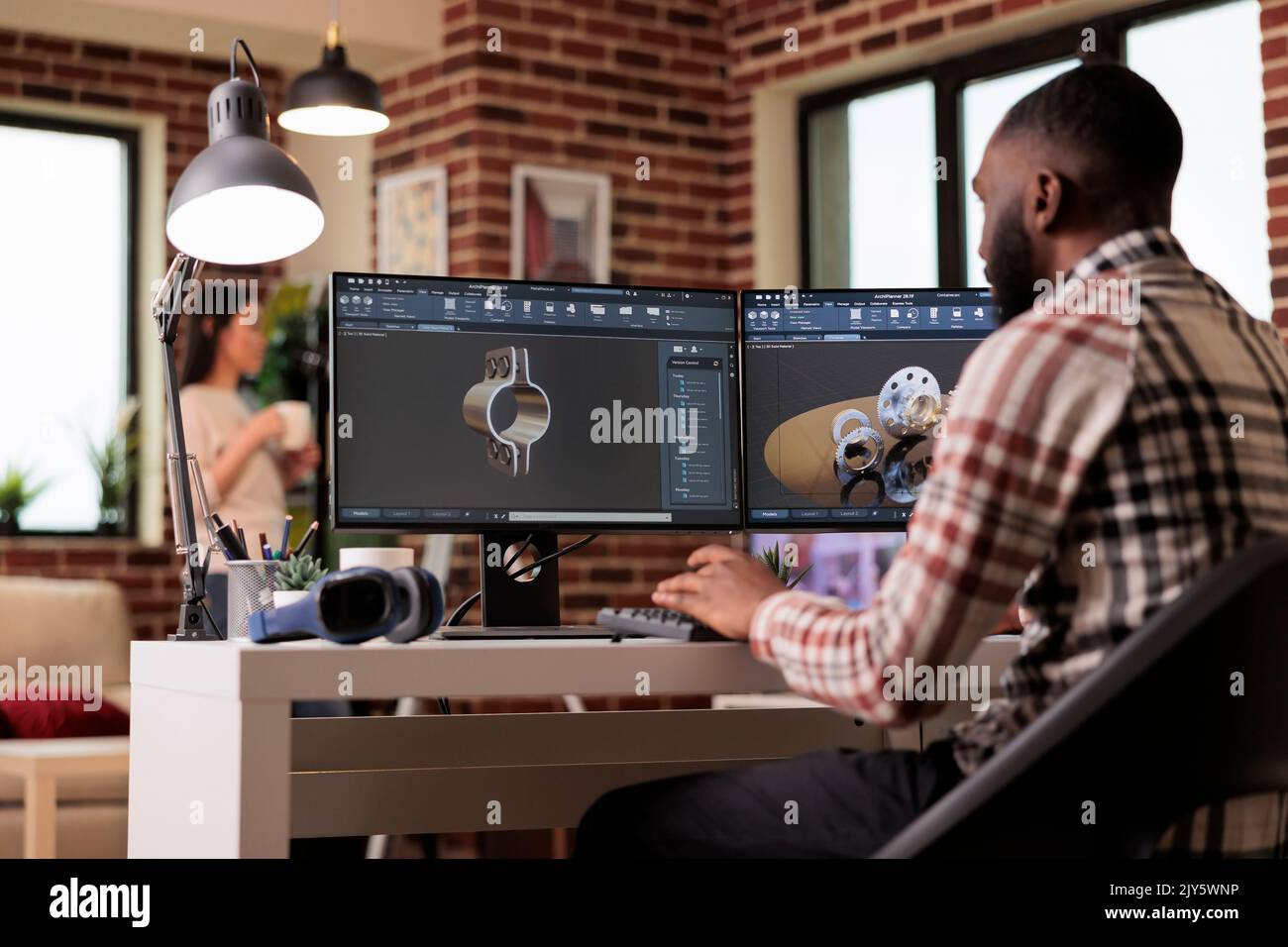 Male developer working with manufacturing software to develop industrial machinery and gears ...