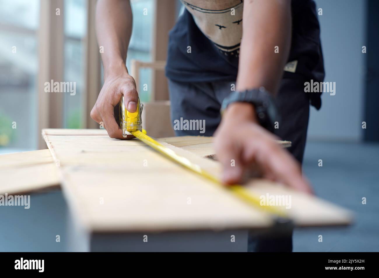 Worker measuring the length of a wooden deck with a tape measure in a ...