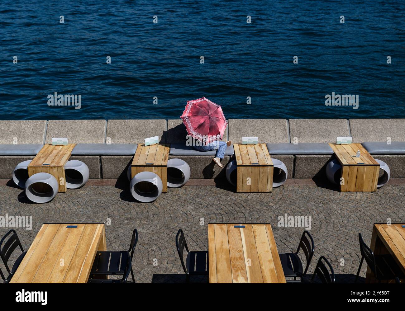 A tourist uses an umbrella to hide from the sun outside the Sydney ...