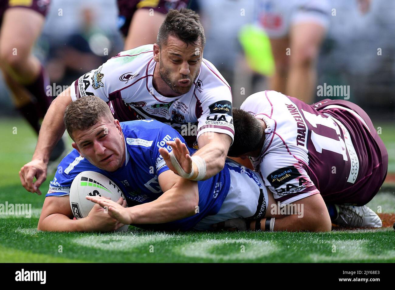 Billy Magoulias of the Jets is tackled by Matthew Robinson (left) and ...