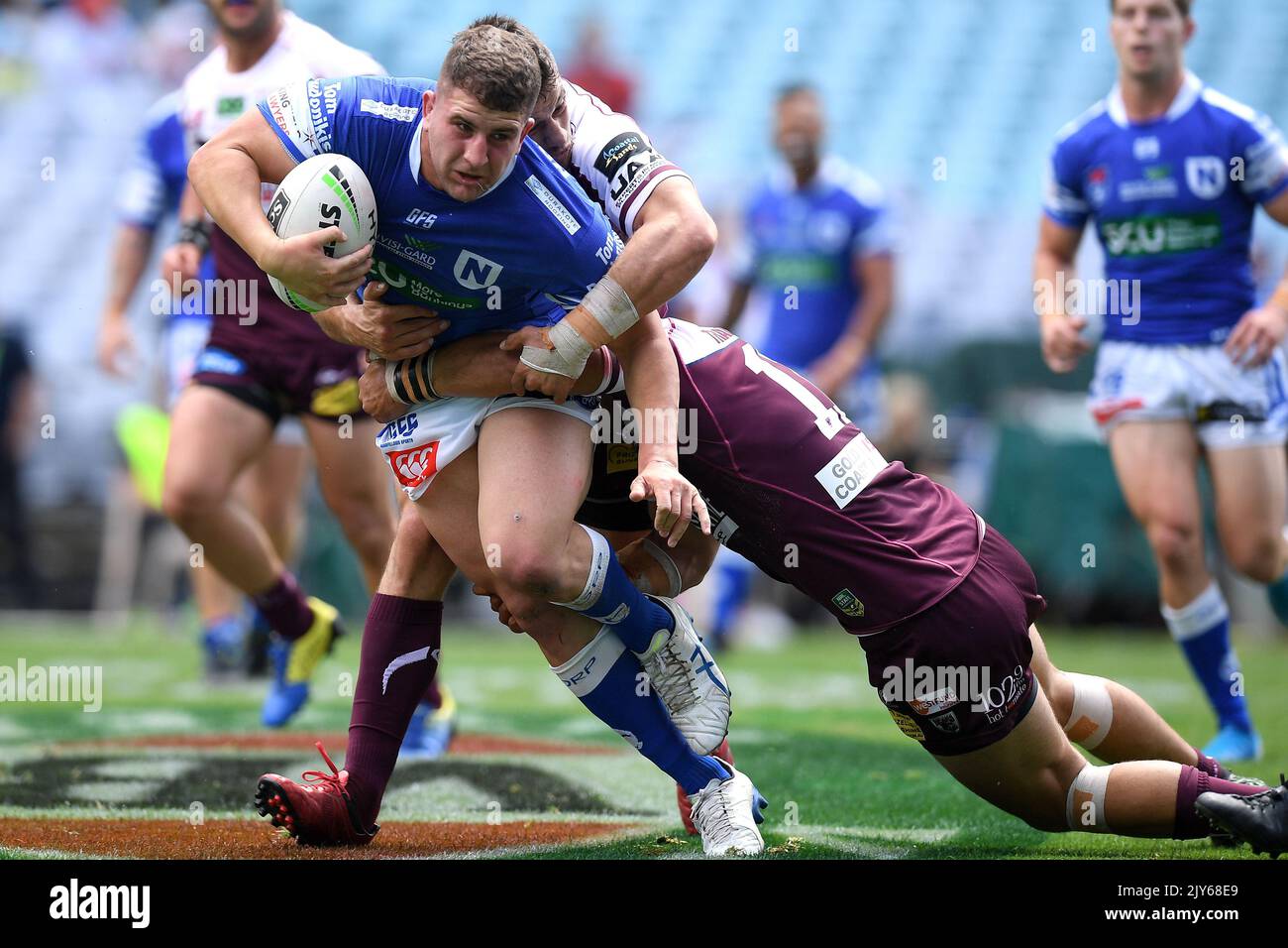Billy Magoulias of the Jets is tackled by Matthew Robinson (left) and ...