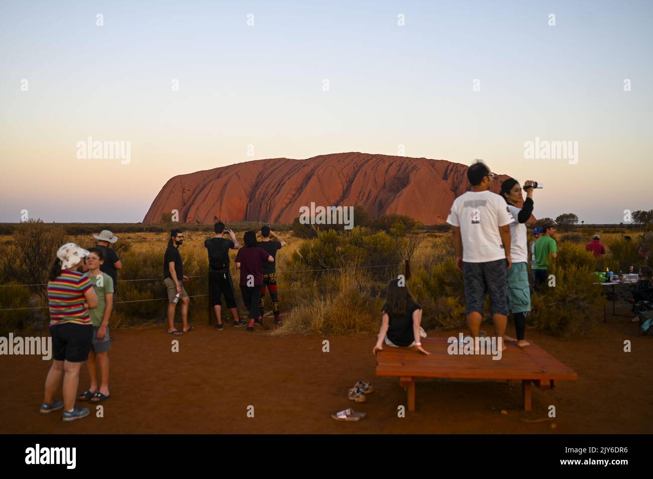 Tourists observe Uluru, also known as Ayers Rock during sunset at Uluru ...