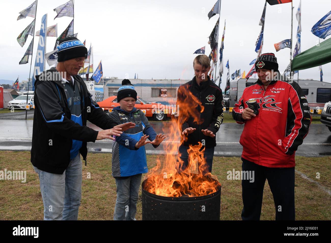 Racegoers warm up by the fire at their campsite during the 2019 ...