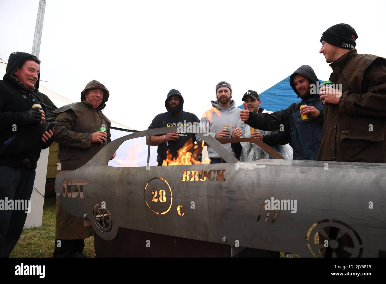 Racegoers warm up by the fire at their campsite during the 2019 ...