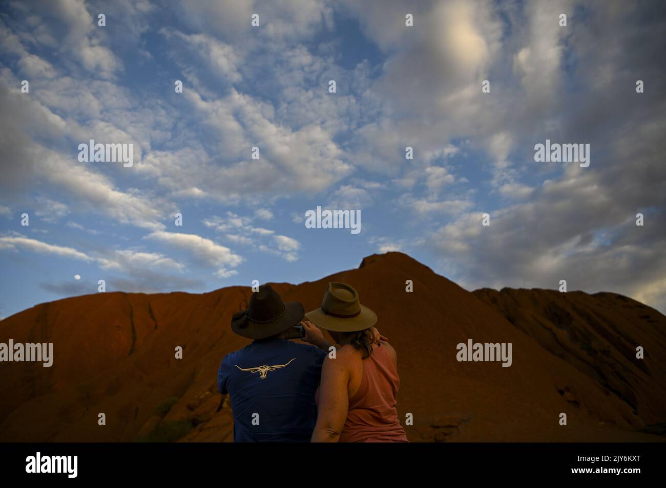 Tourists take photographs near the climbing area at Uluru, also known ...