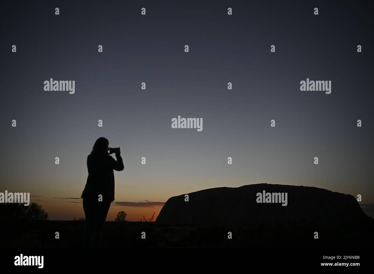 A tourist takes photographs of Uluru, also known as Ayers Rock during ...