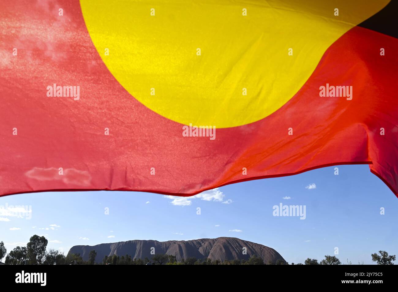 Uluru, also known as Ayers Rock is seen under the Aboriginal flag ...